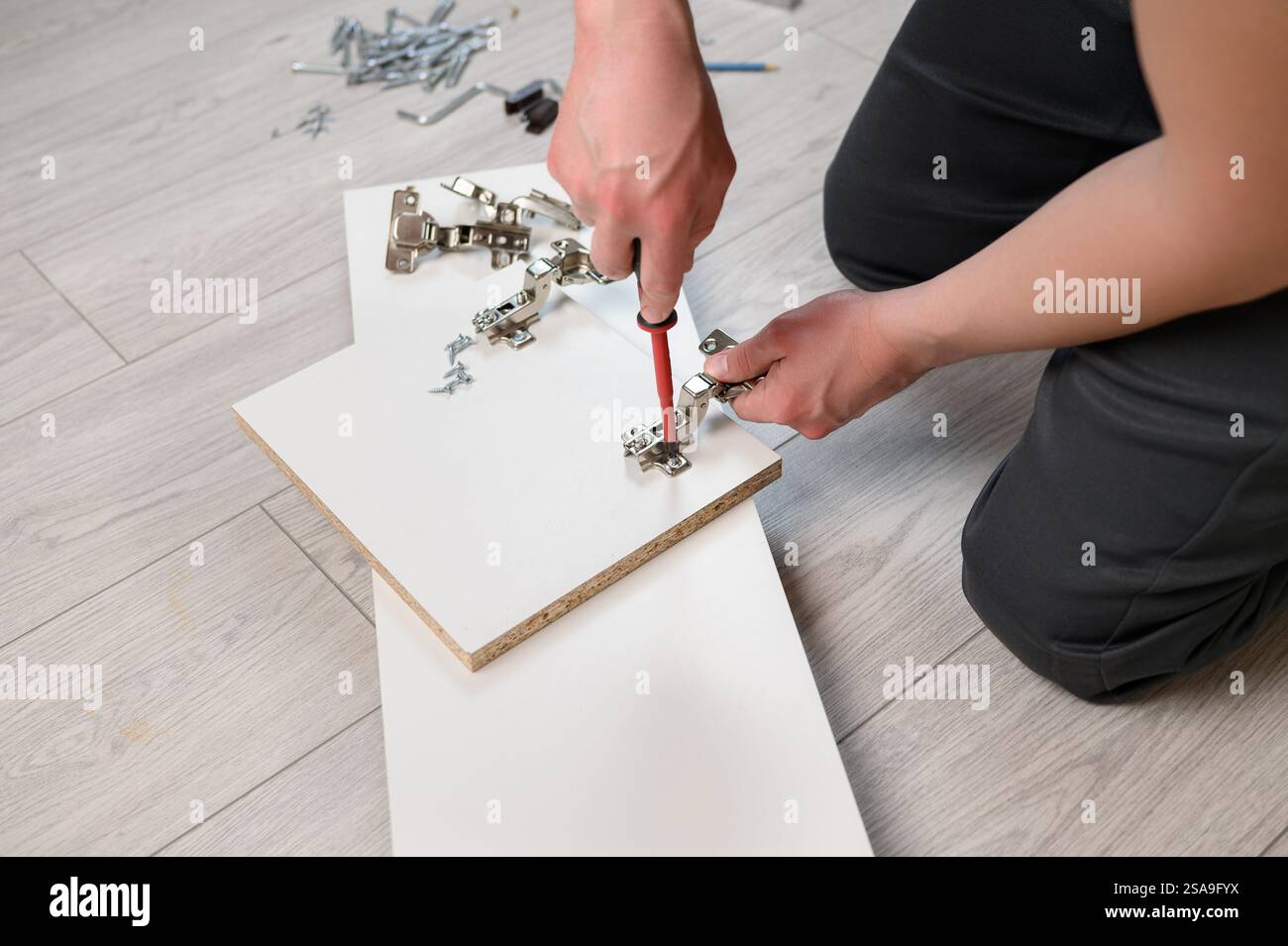 Assembling furniture. A worker inserts a hinge into a wooden closet ...