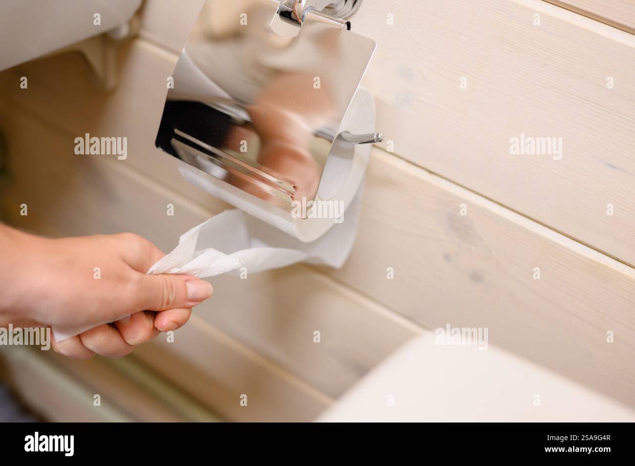 Woman tears toilet paper, squeezing it tightly, from a toilet paper ...