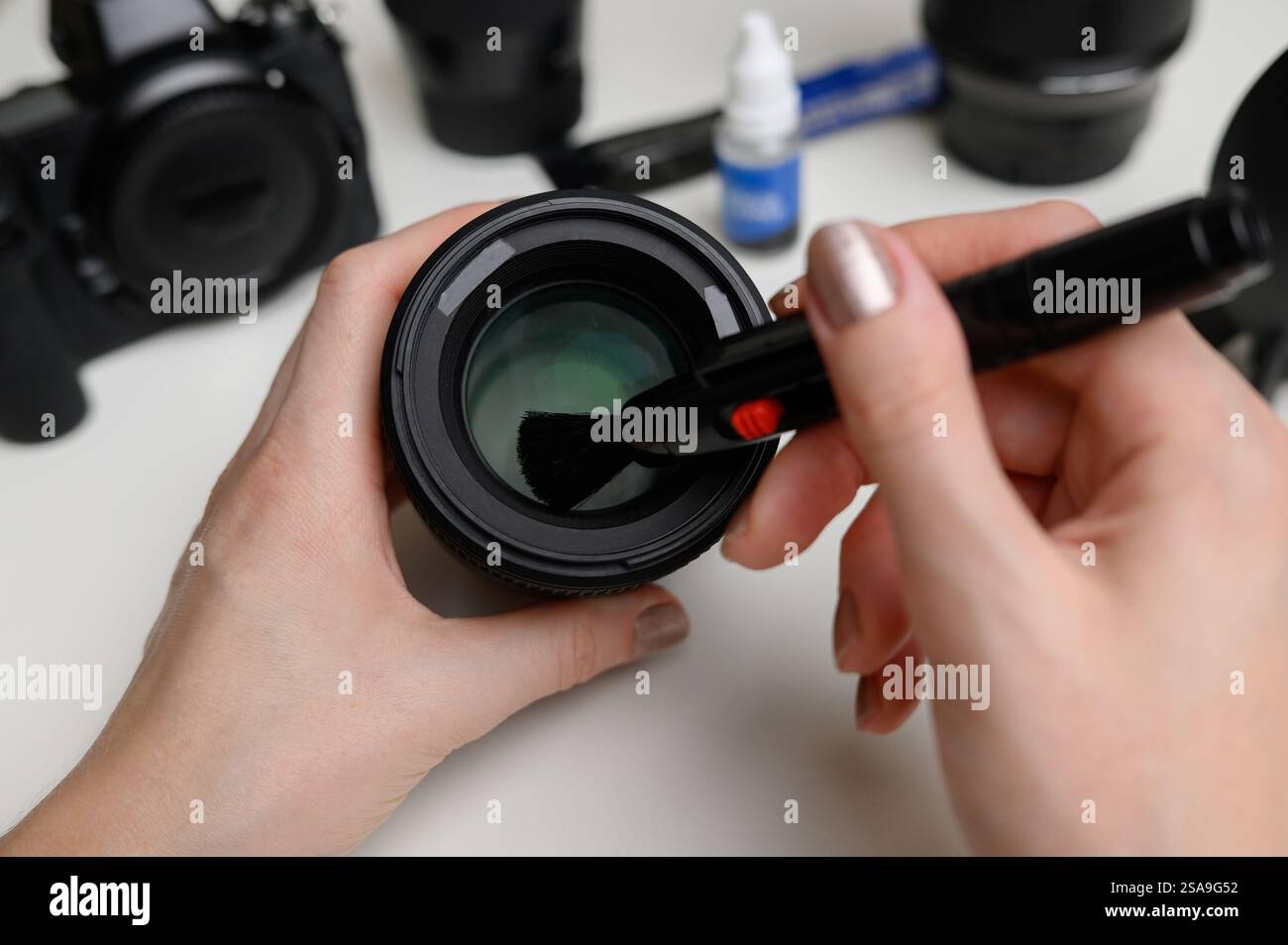 Hands cleaning the lens of a digital camera from dust with a special ...