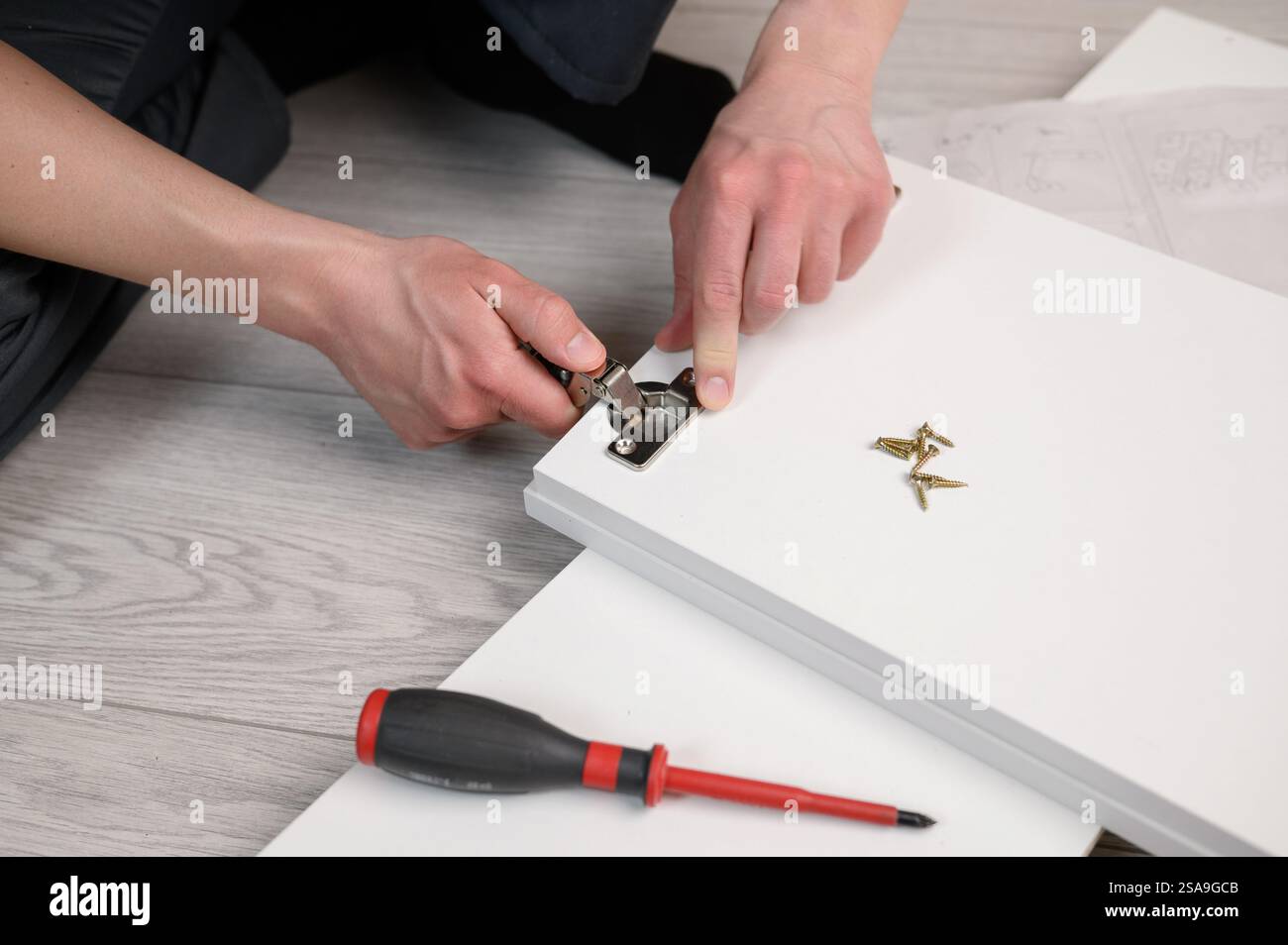 Assembling furniture. A worker inserts a hinge into a wooden closet ...