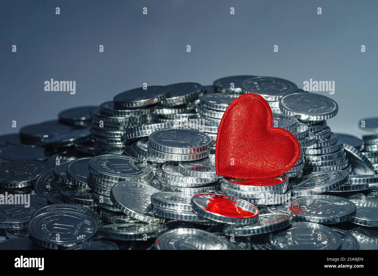 Red heart on pile of shiny coins. Dark blue background. Valentine's Day ...