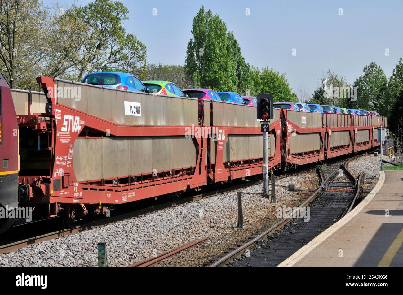 Close up double decker wagons on freight train transporting load of new cars travelling through ...