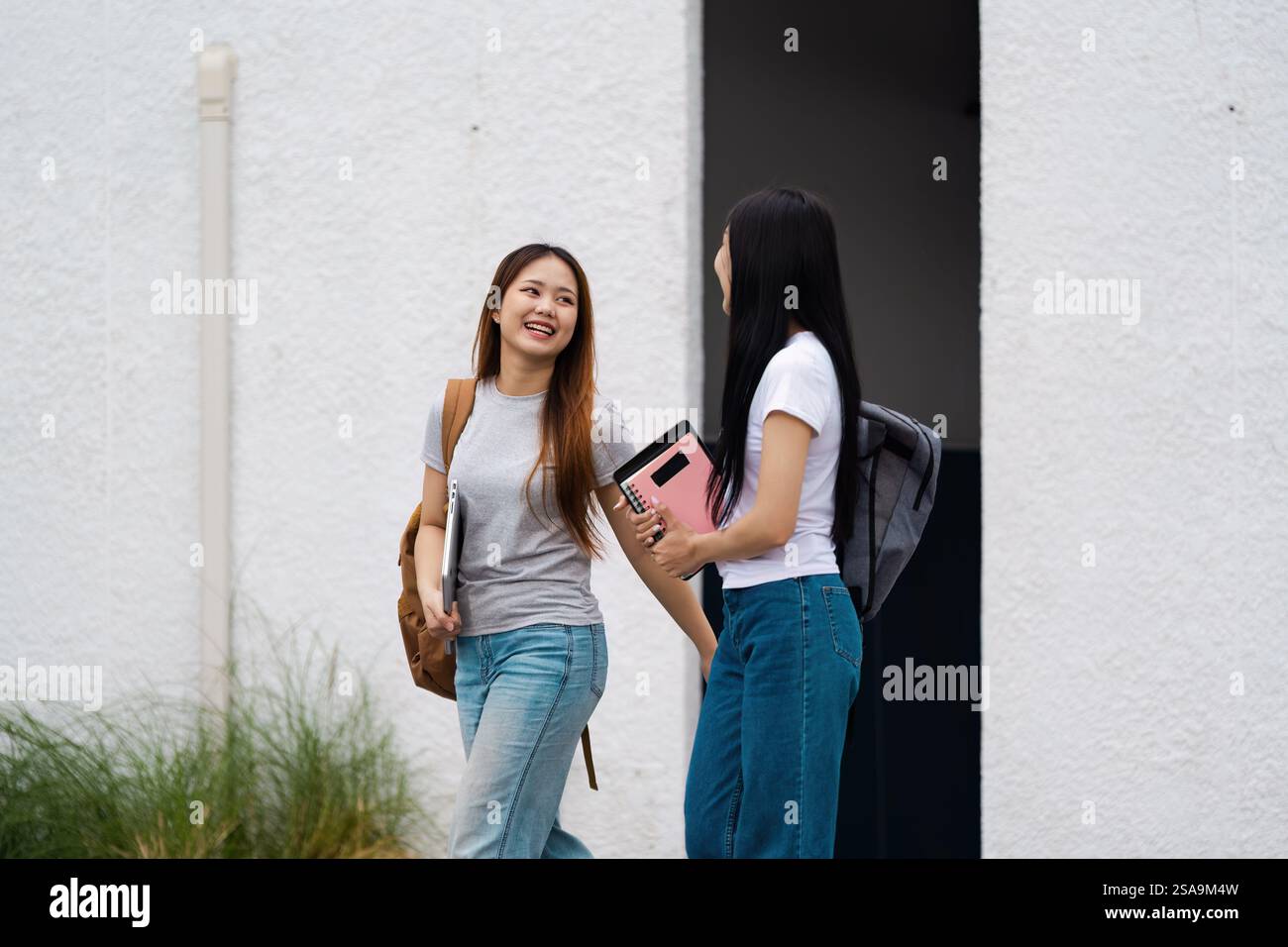 Two cheerful students walking together with backpacks, enjoying their time on campus after class ...