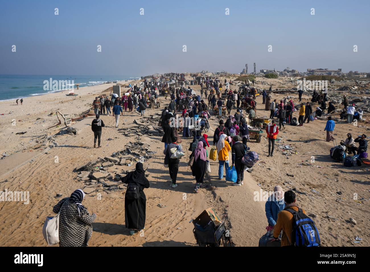 Displaced Palestinians walk on a road in central Gaza to return to ...