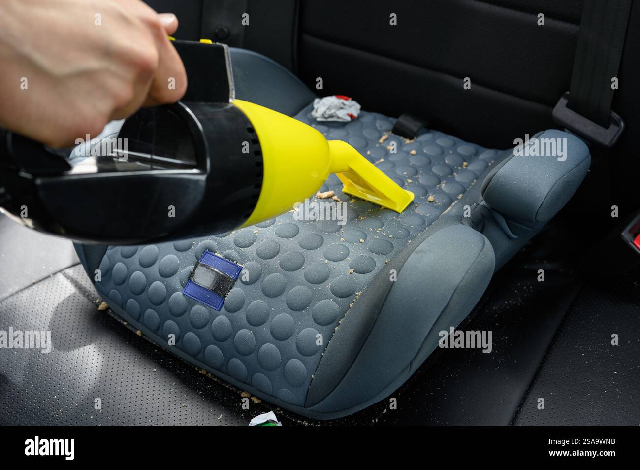 Cleaning child booster seat with vacuum cleaner. Service worker cleans ...
