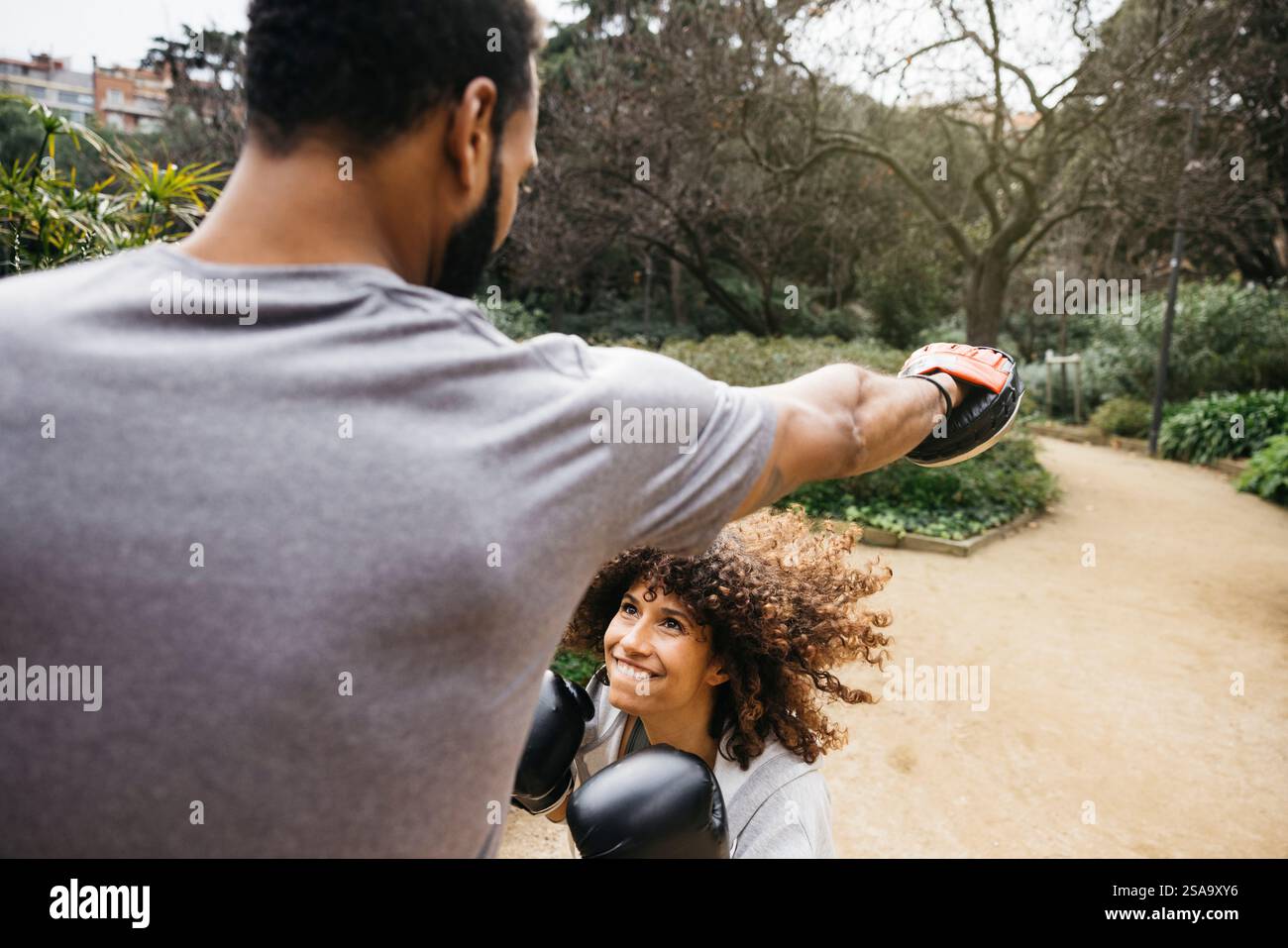 A woman practicing boxing techniques with her coach using boxing gloves ...