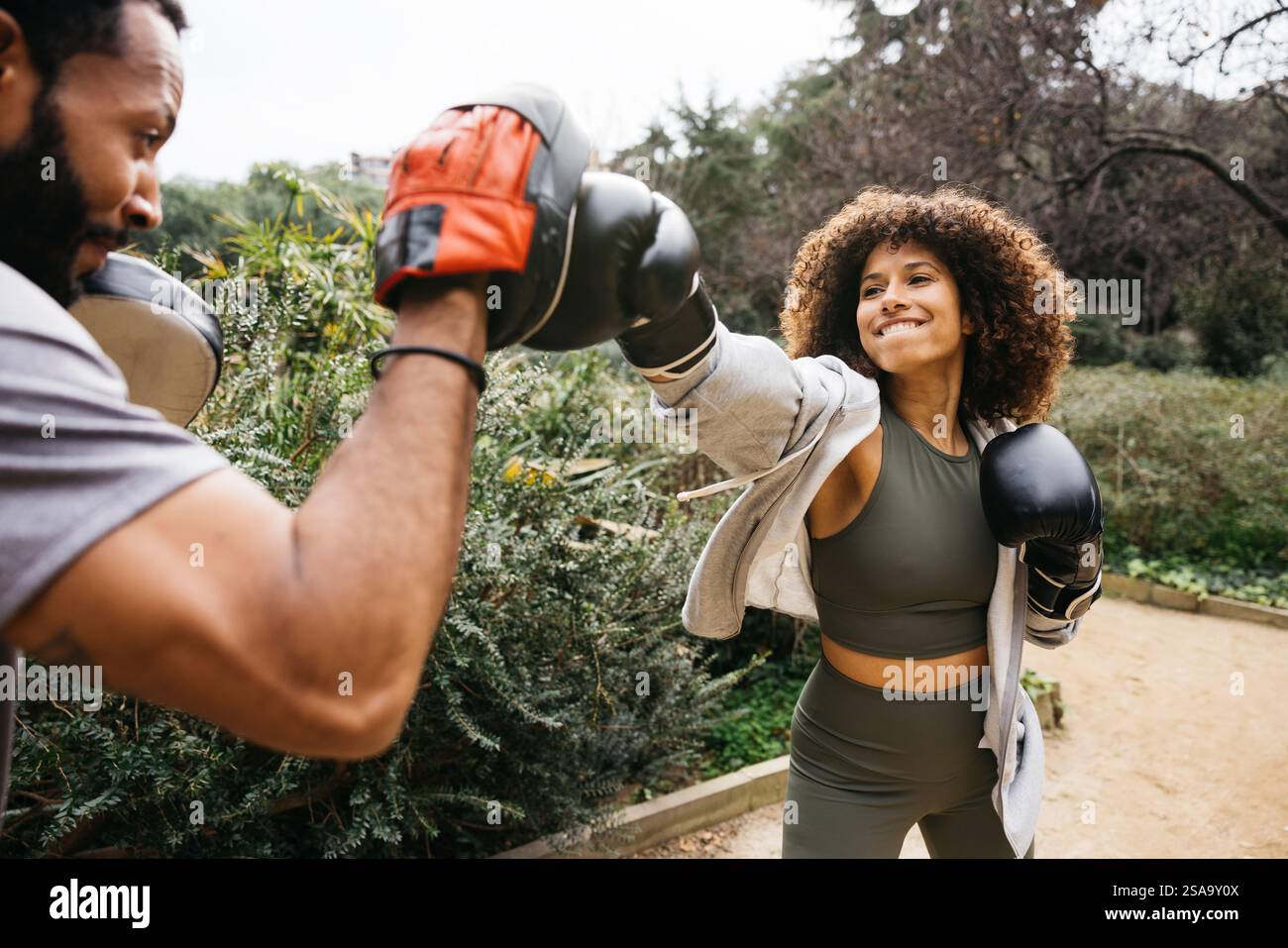 Young woman boxing with her trainer in a urban park, showcasing ...
