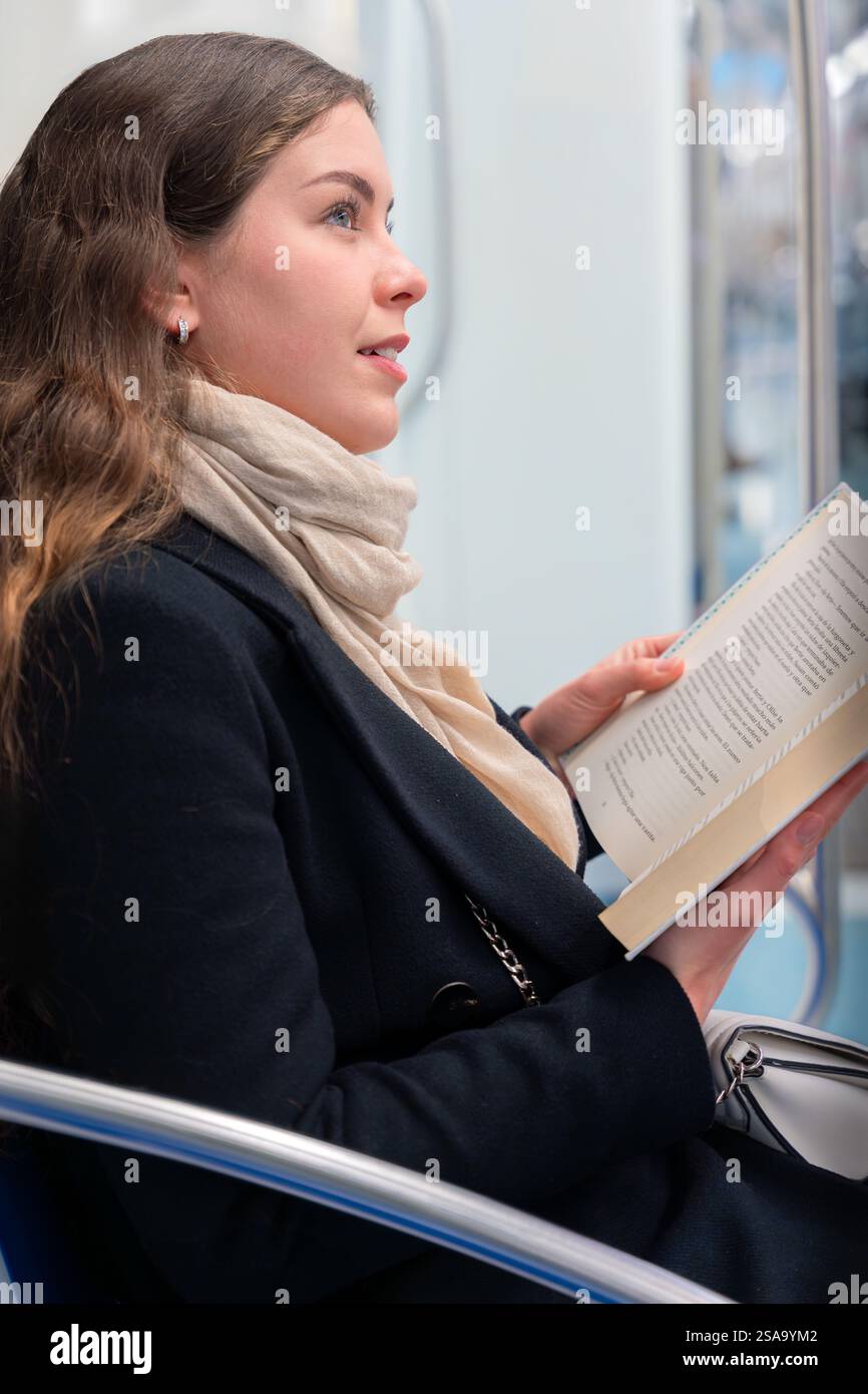 Side view Young Woman Reading a Book While Traveling on a Subway Train ...