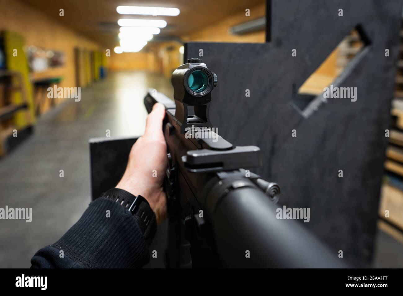 Aiming a tactical rifle with a red dot sight at a target in a shooting ...