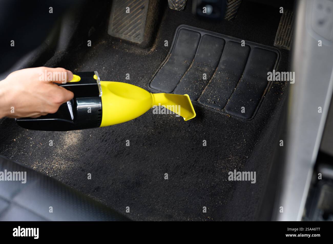 Car interior cleaning, close-up. Man vacuuming floor in car cabin with ...