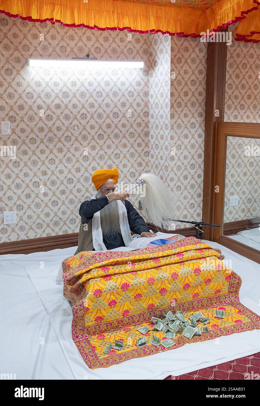 A Sikh priest waves his Chaur Sahib fly whisk at an Akhand Path service ...