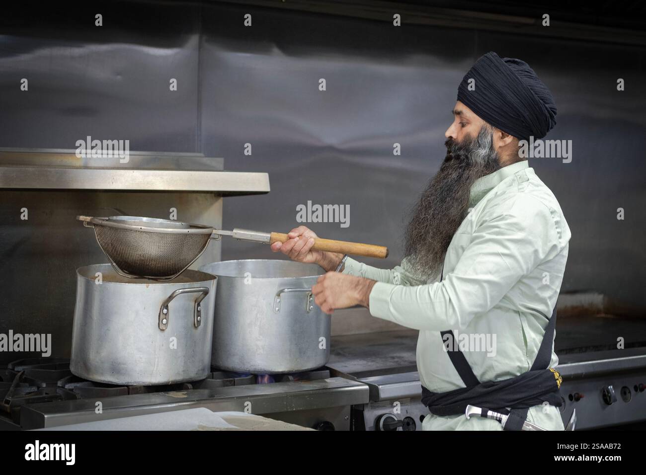 A Sikh priest volunteers in the temple kitchen preparing foos for the ...