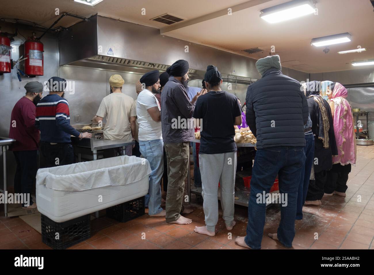 Men & women of various ages prepare roti breads to distribute at a ...