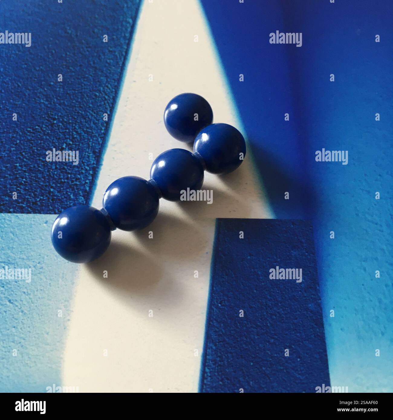 Minimalist composition featuring a set of blue spheres arranged on a vibrant abstract background ...