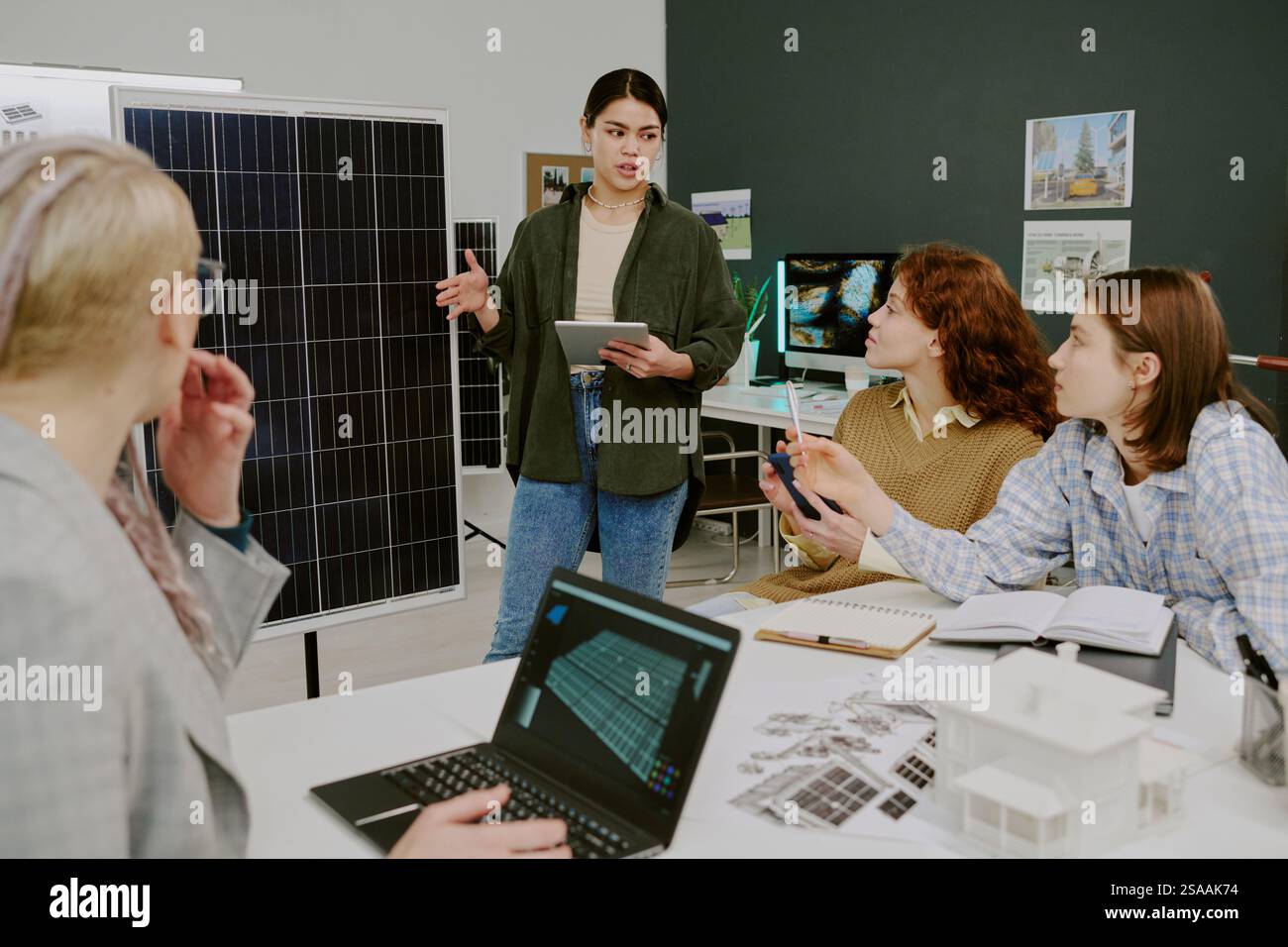 Woman presenting renewable energy project to diverse team using a ...