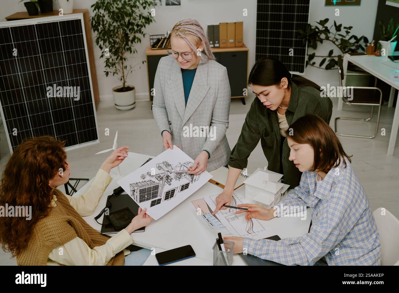 Group of four young women collaborating on sustainable energy project ...