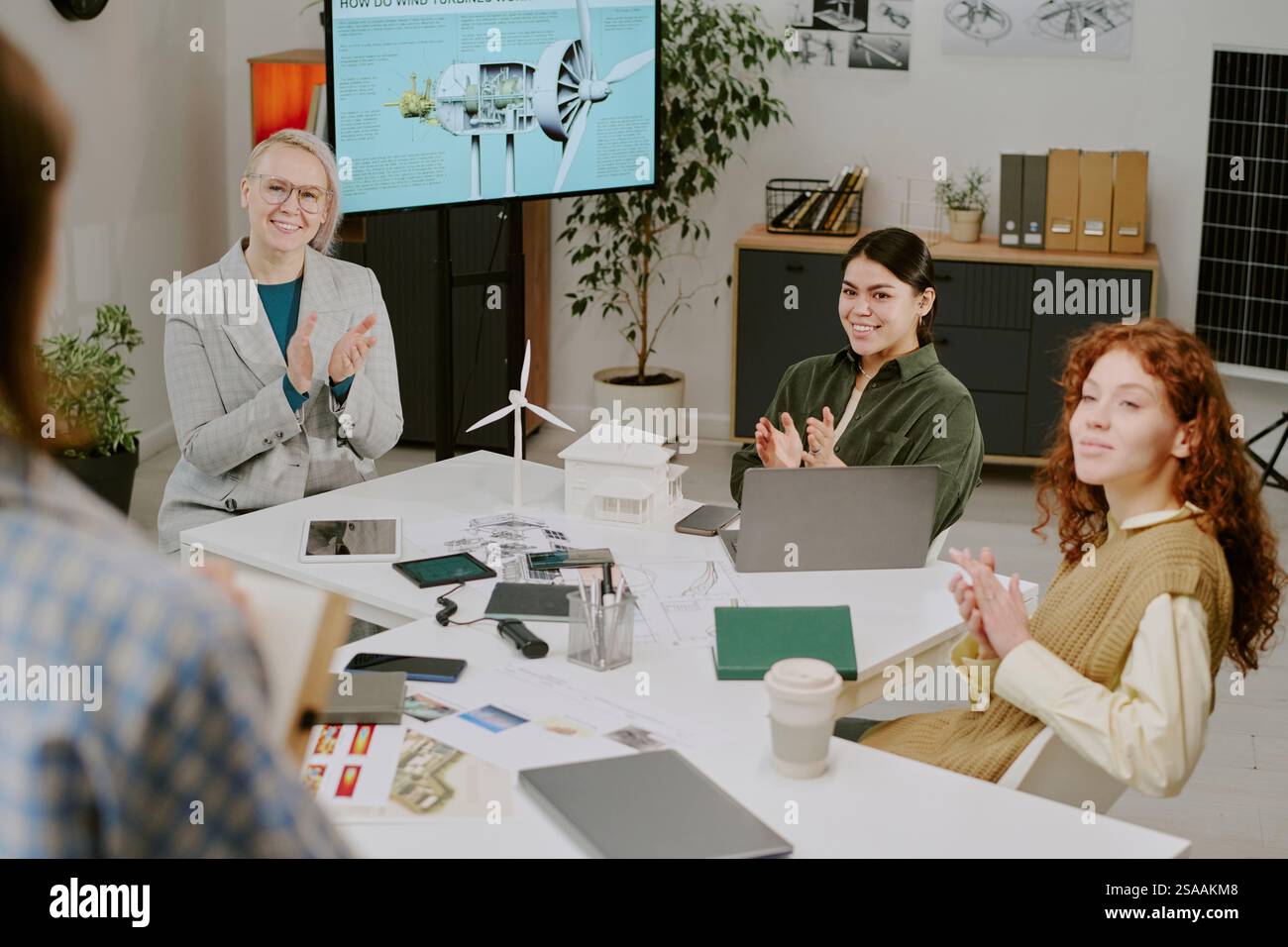 Group of professionals applauding colleague during presentation in ...