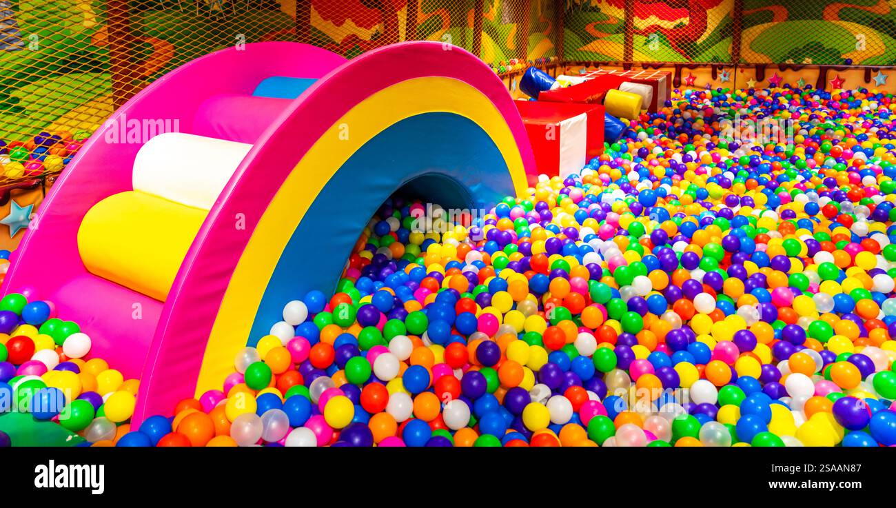 Rainbow slide leading into a vibrant and colorful ball pit for kids ...