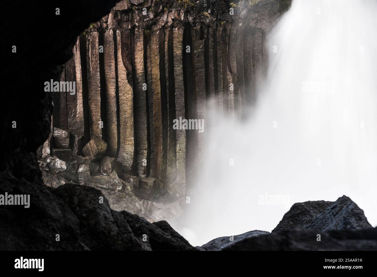 Water cascades dramatically over towering hexagonal basalt columns ...
