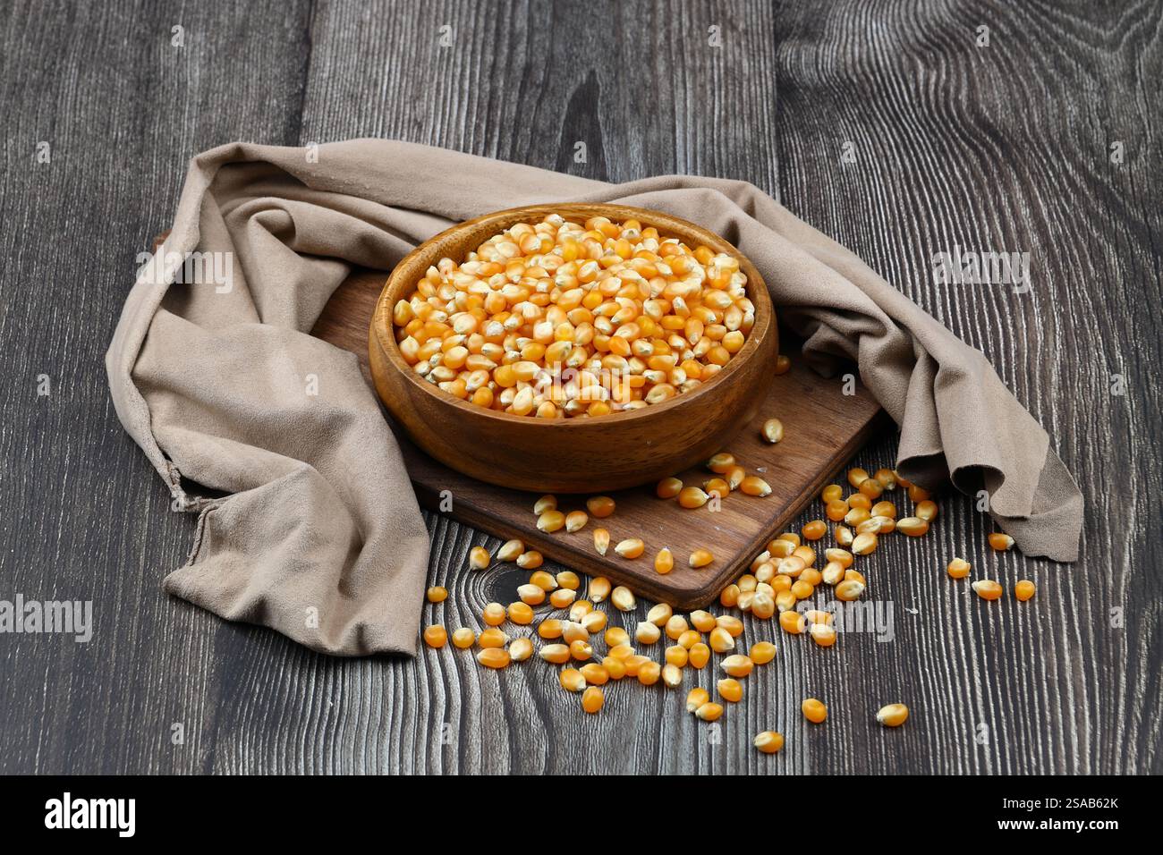 Unpopped popcorn in a wooden bowl on wooden background. A type of corn ...