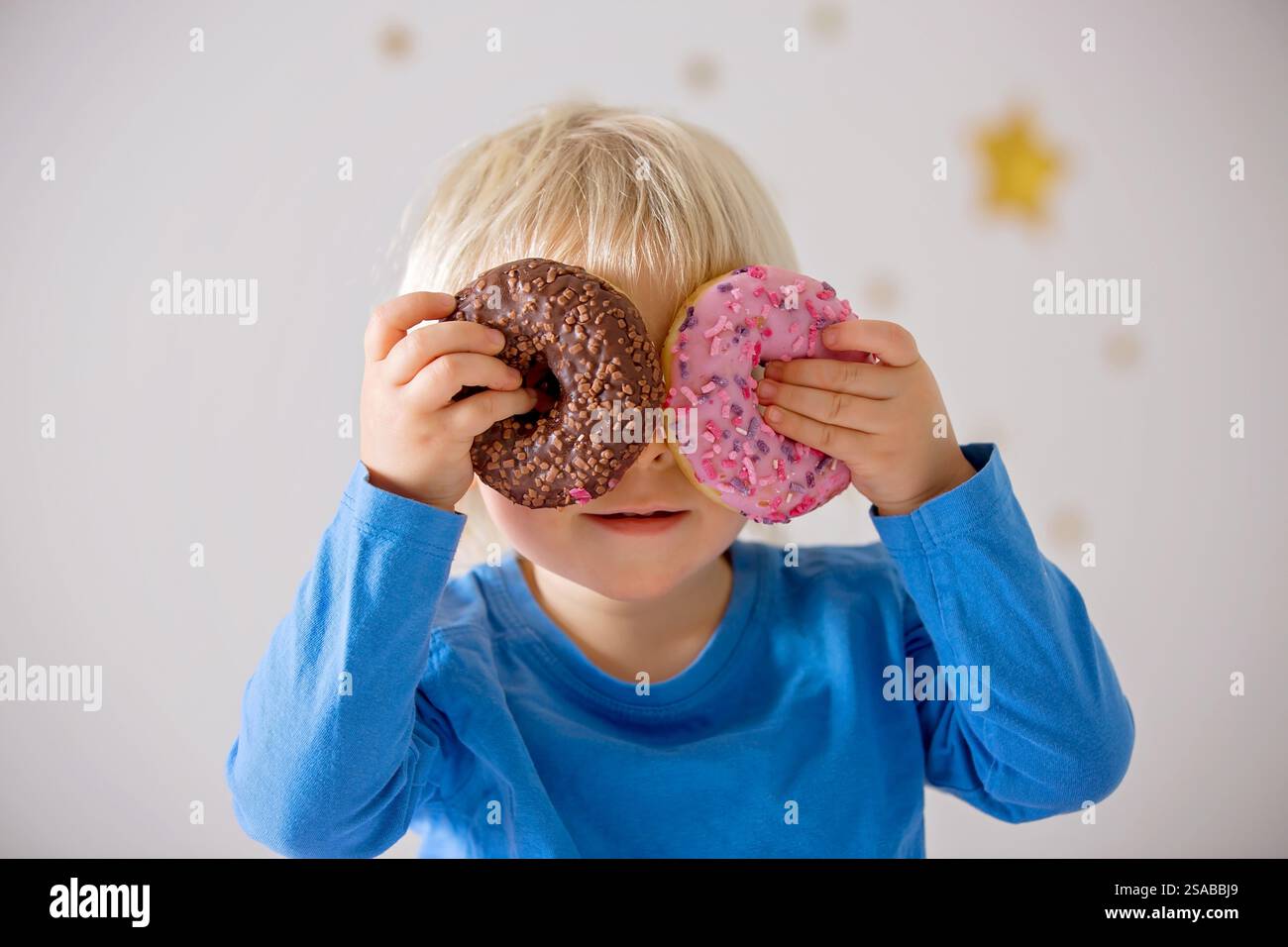 Cute sweet blonde child, playing and eating donuts at home Stock Photo ...