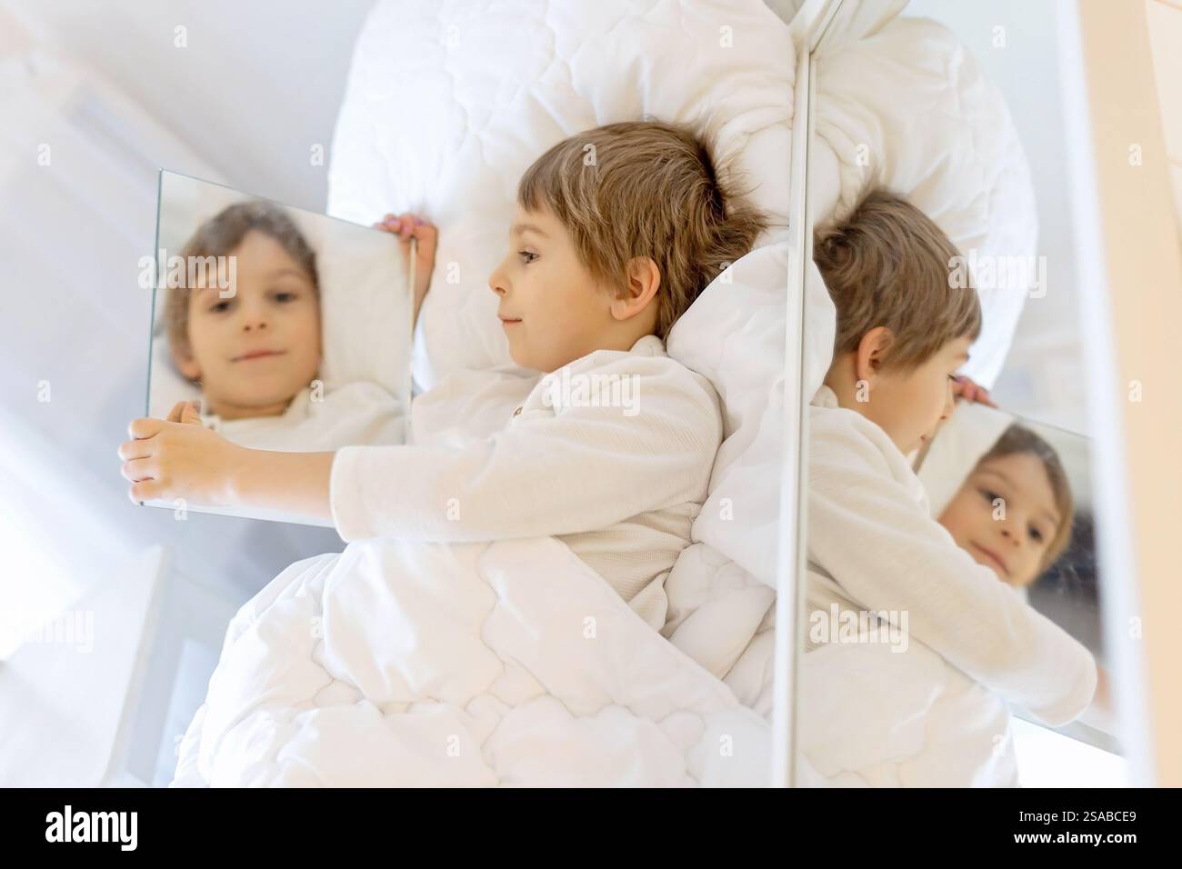 Portrait with mirrors of a child, lying in bed, reflection of his face ...