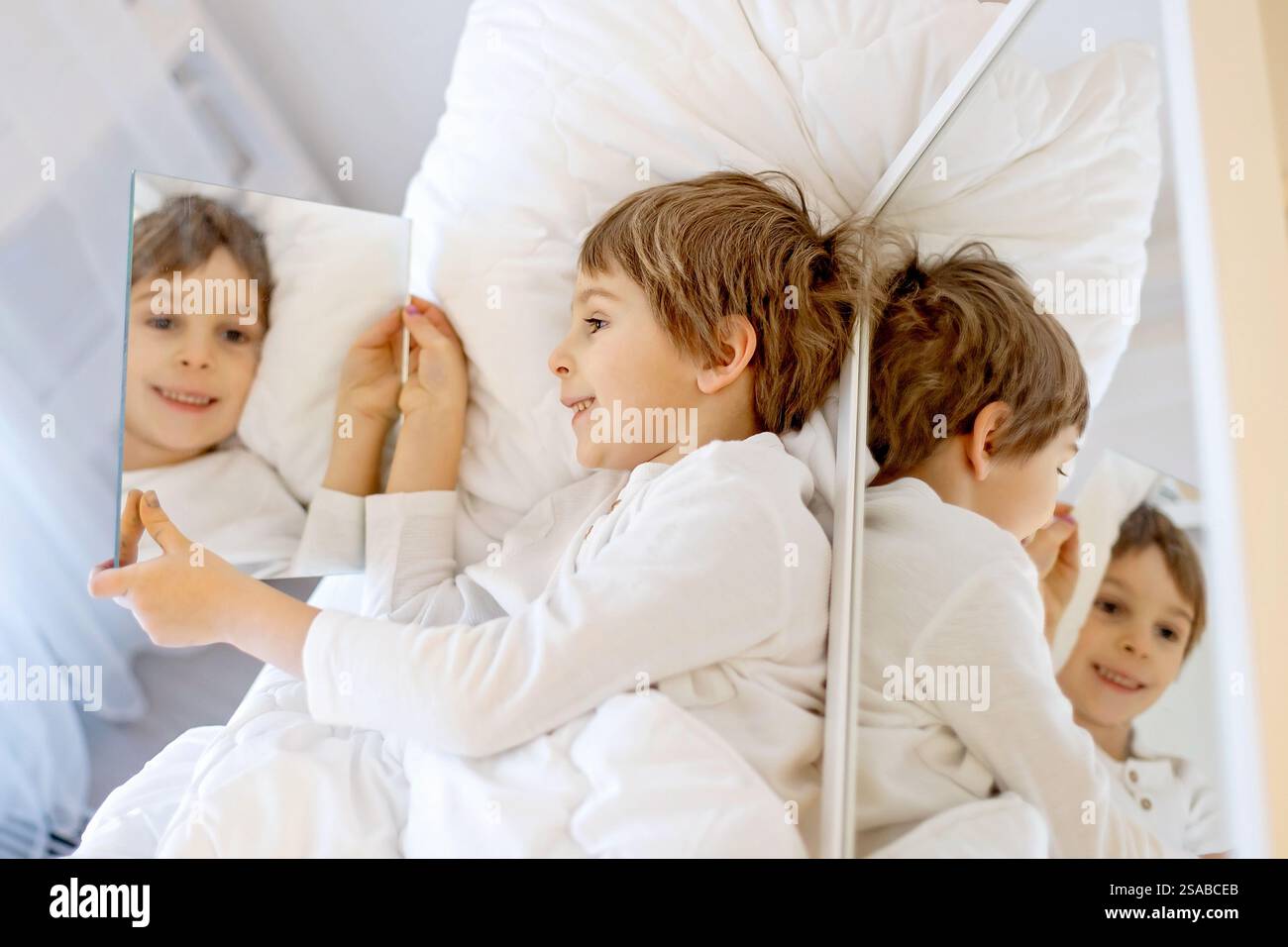 Portrait with mirrors of a child, lying in bed, reflection of his face ...