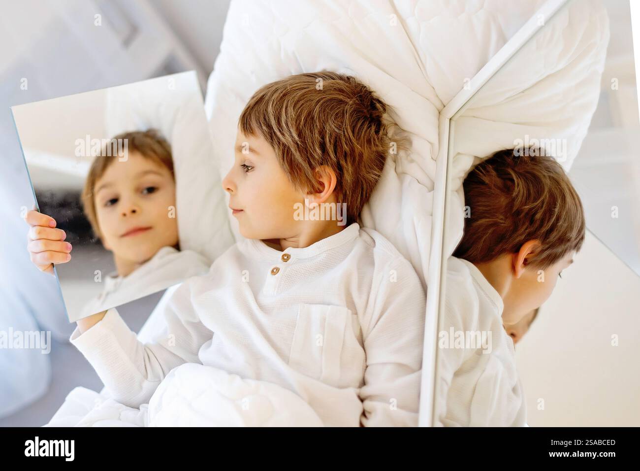 Portrait with mirrors of a child, lying in bed, reflection of his face ...
