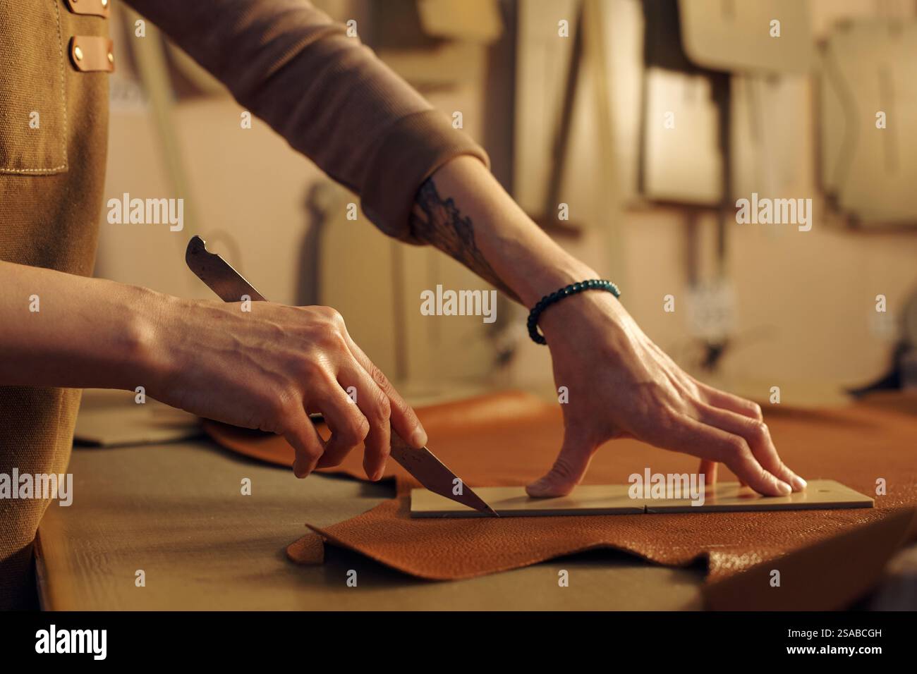 Artisan carefully cutting leather with sharp tool, focusing on detailed ...