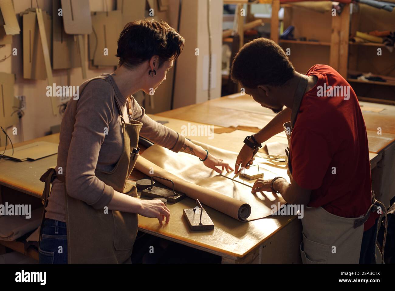 Two people working together on paper patterns inside a workshop ...
