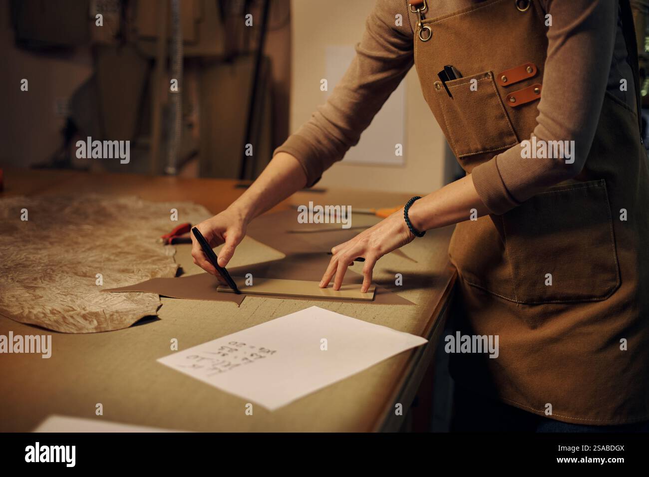 Individual standing at workbench in studio cutting fabric pattern with ...