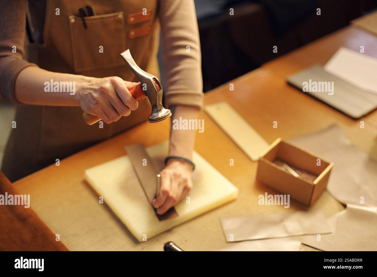 Person meticulously crafting leather goods on workspace with various ...