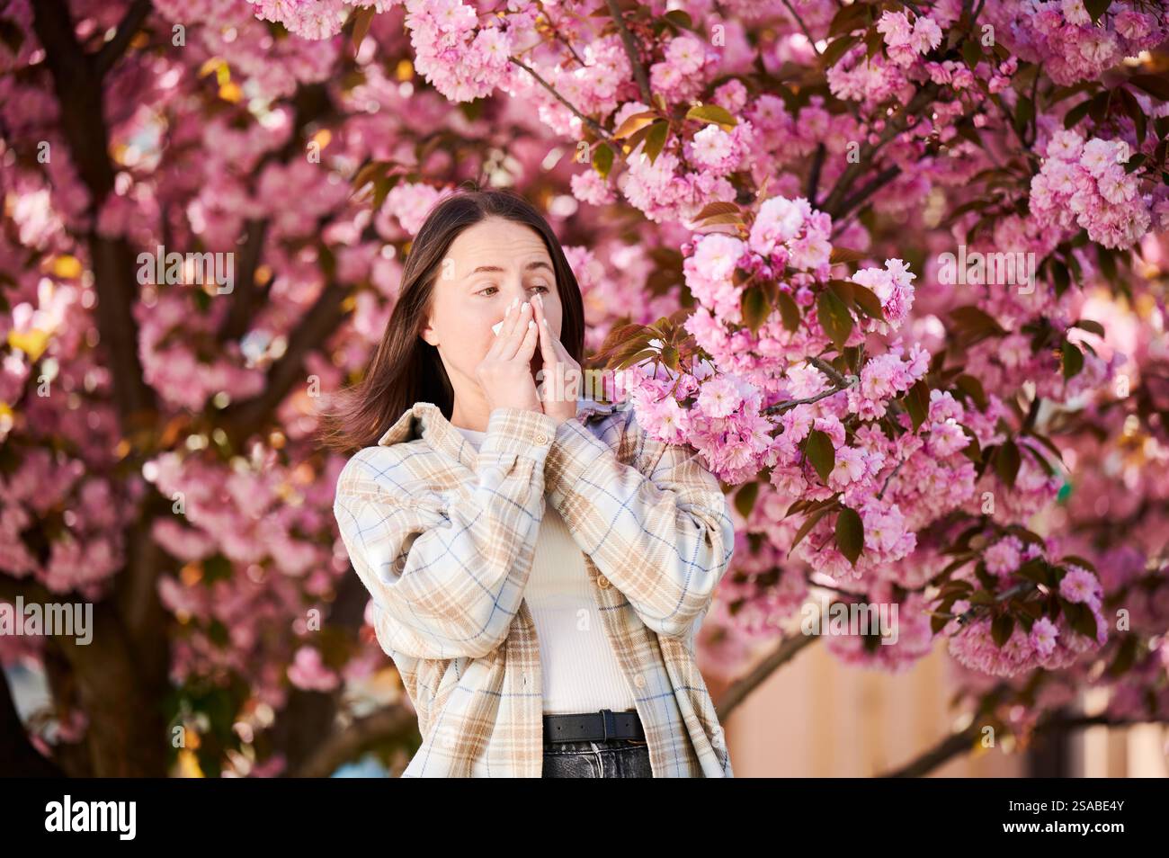 Woman allergic suffering from seasonal allergy at spring in blossoming ...