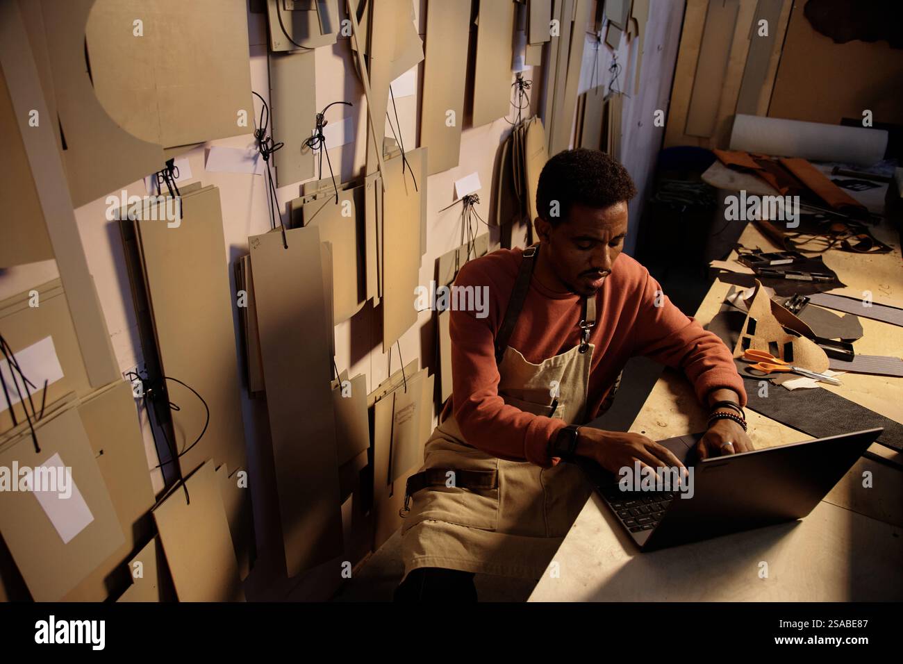 Person working on laptop in workshop surrounded by various materials ...