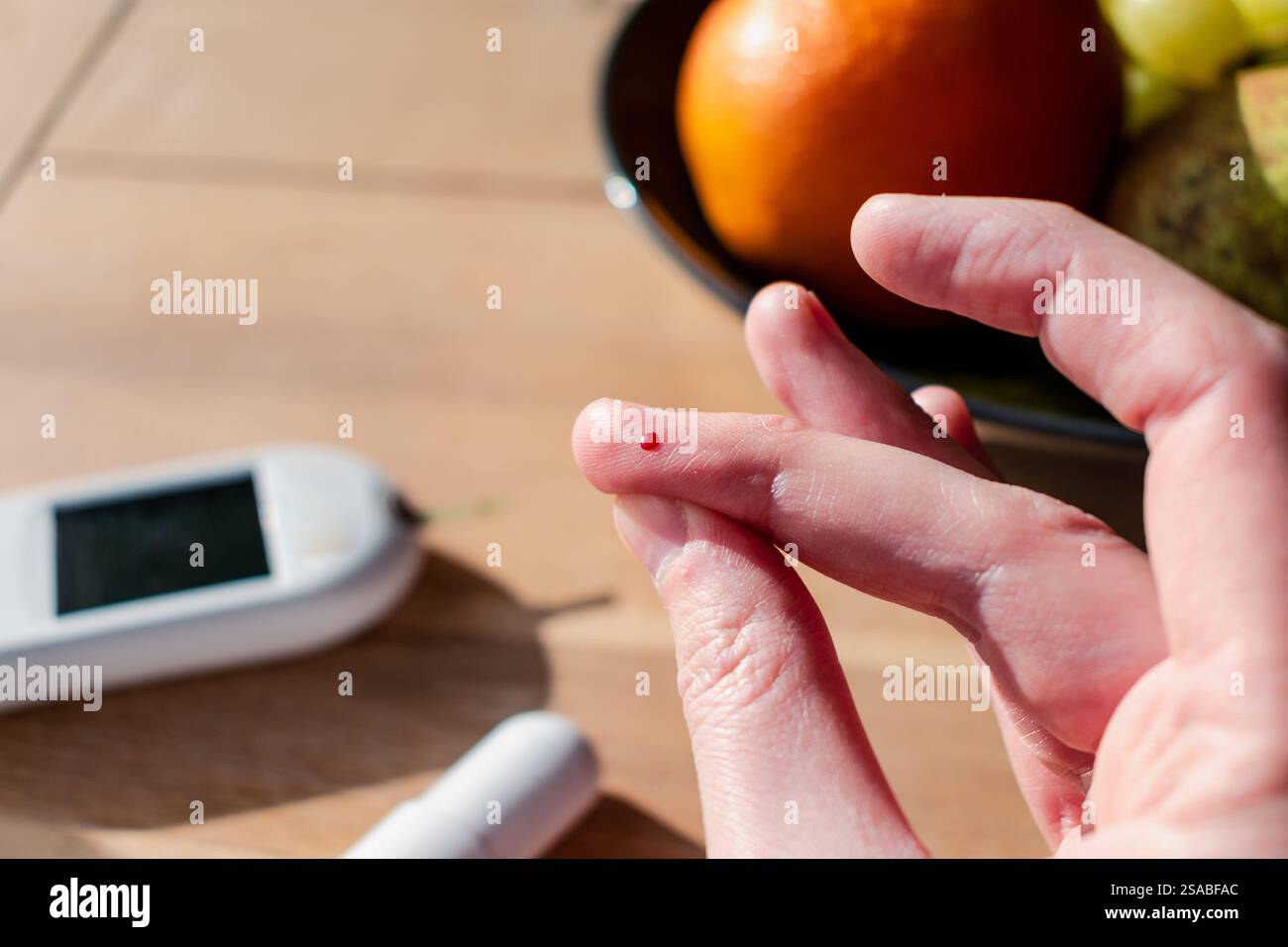 Woman pricking her finger to check blood glucose level with glucometer ...