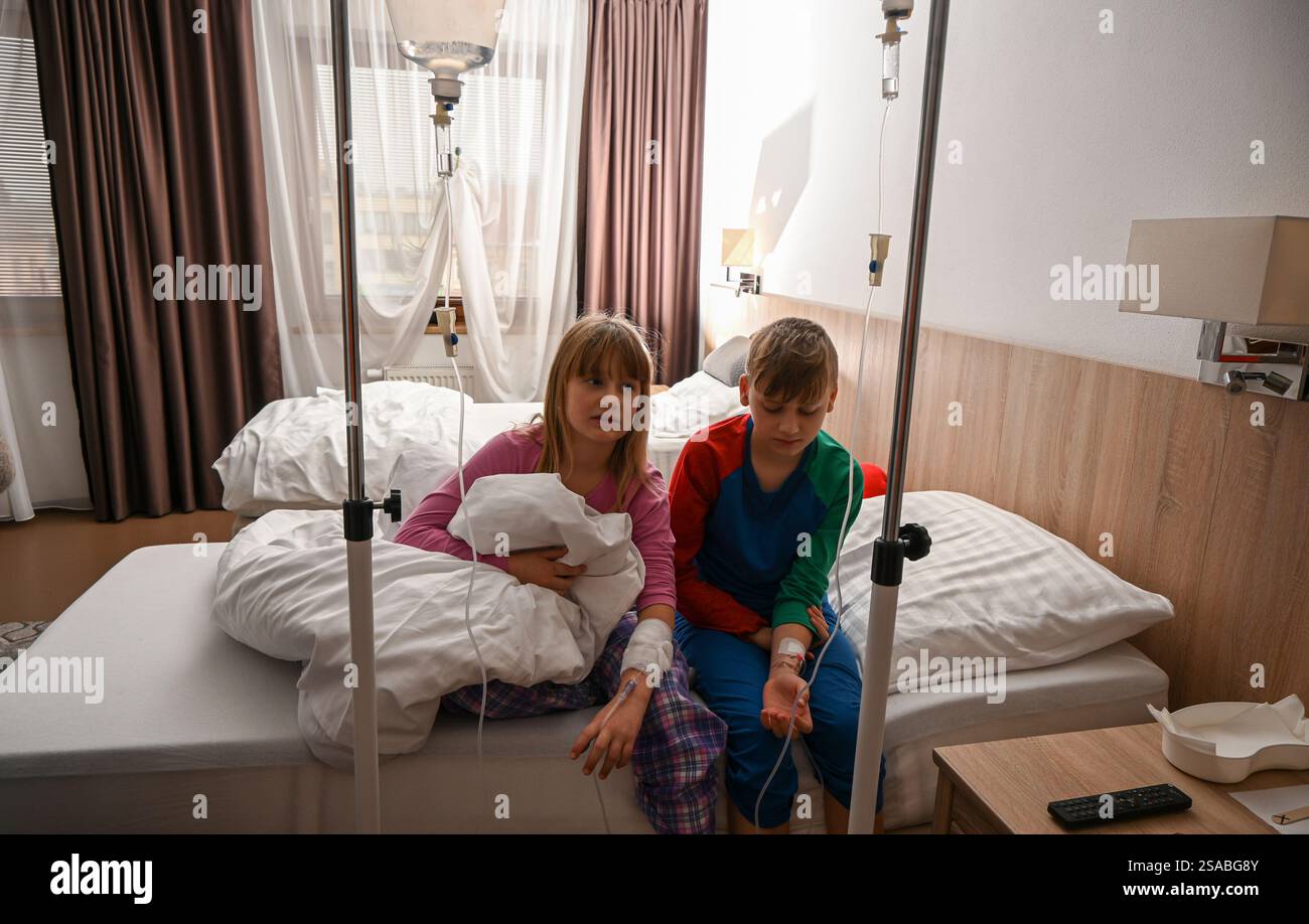 Two young children are receiving intravenous fluids while sitting on a ...
