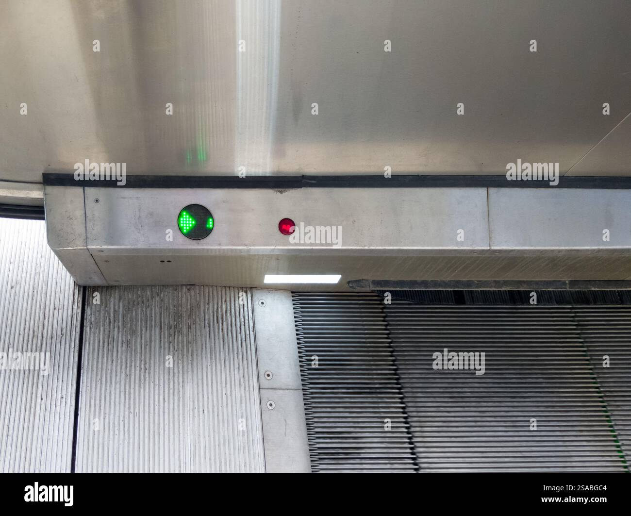 A green arrow directional indicator on an airport escalator, designed ...