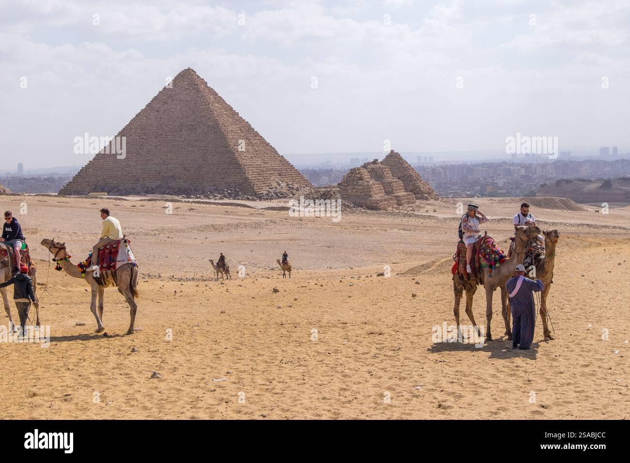 Tourists riding camels in front of the pyramids of Giza, Egypt Stock ...
