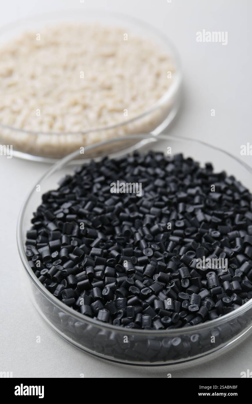 Colorful plastic granules in petri dishes on gray background, closeup ...