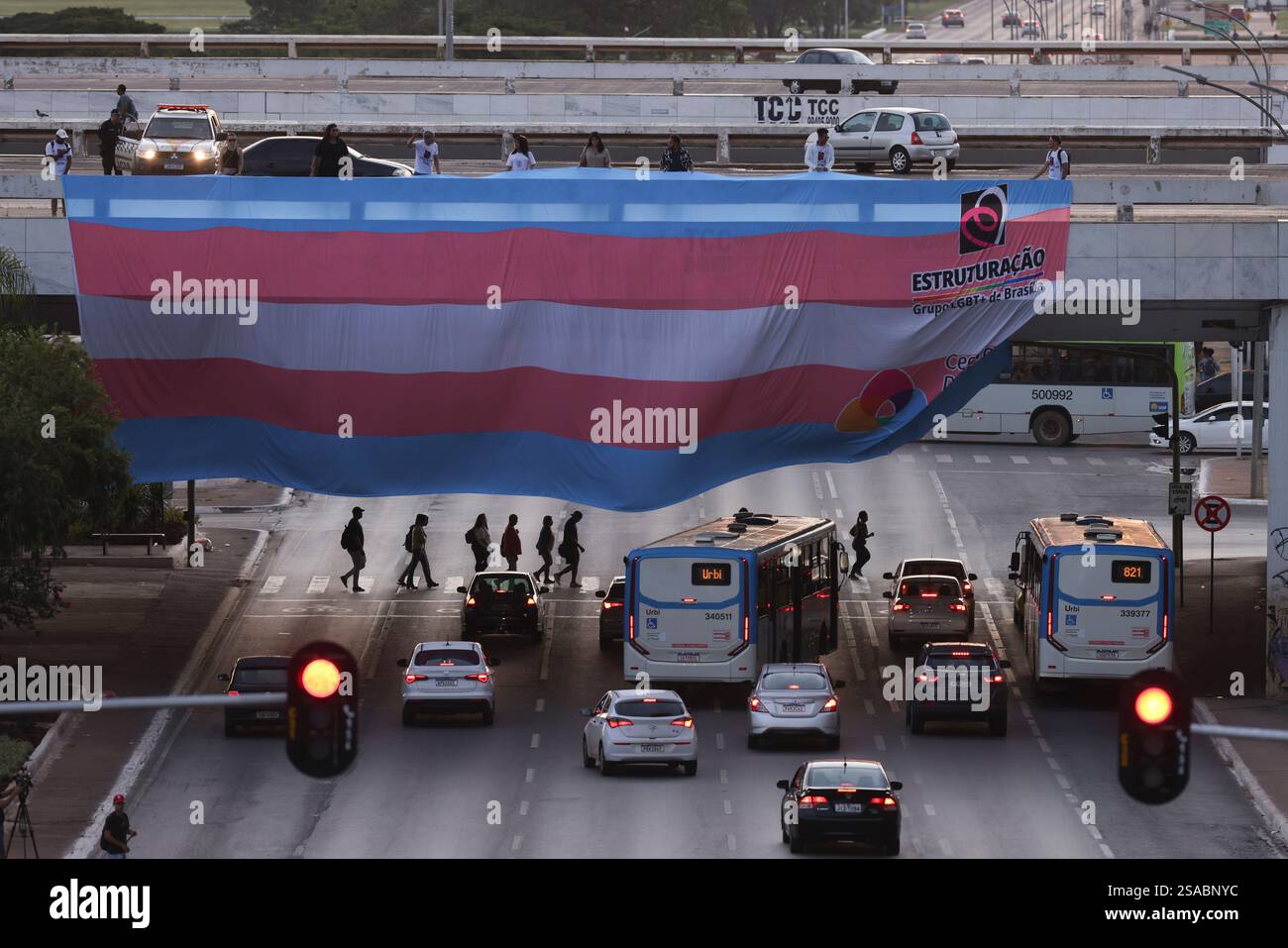 A large transgender flag hangs from a bridge, placed by people on the ...