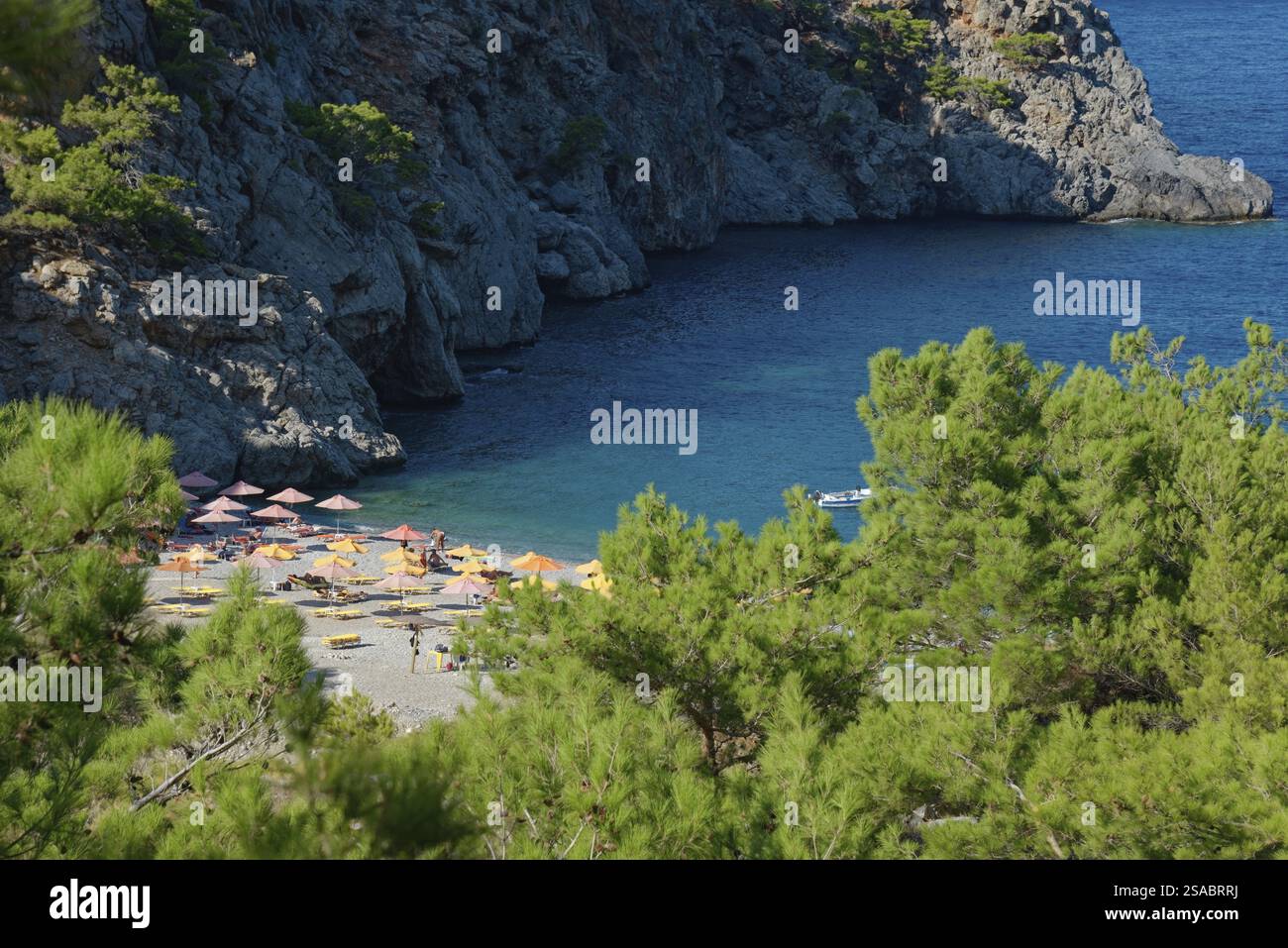 Secluded Ahata Bay surrounded by green pine trees and rocky cliffs with ...