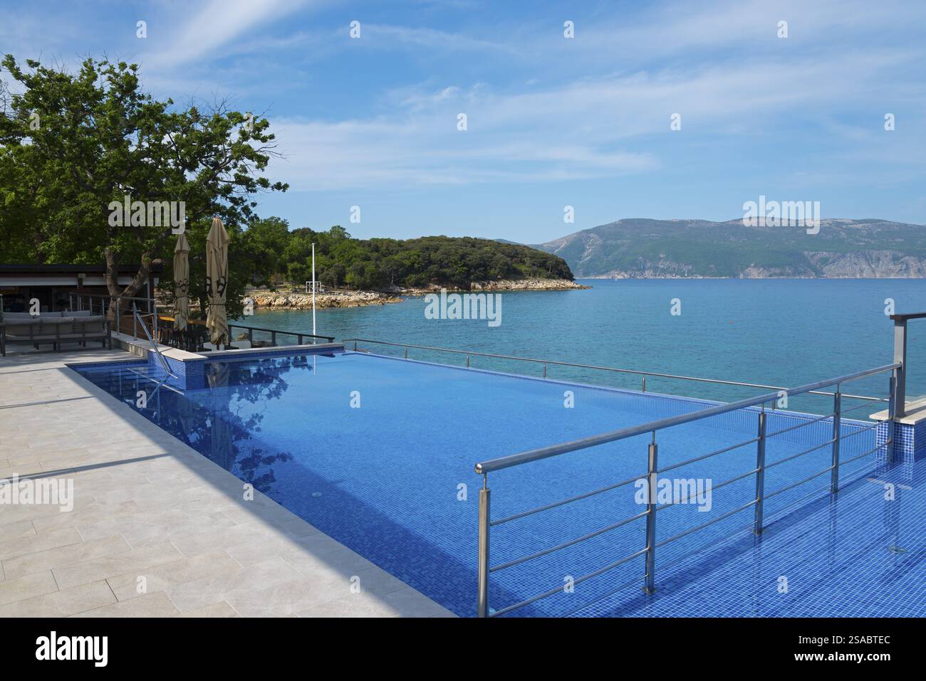 Infinity pool with views of the blue sea and mountains under a clear ...
