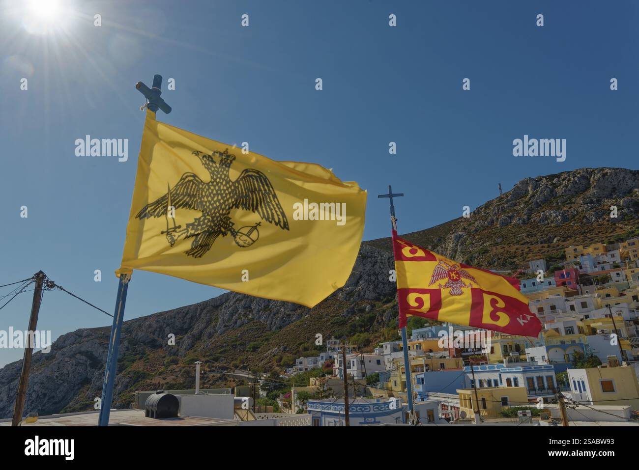 Yellow orthodox flags fly against a sunny sky over a Greek village ...