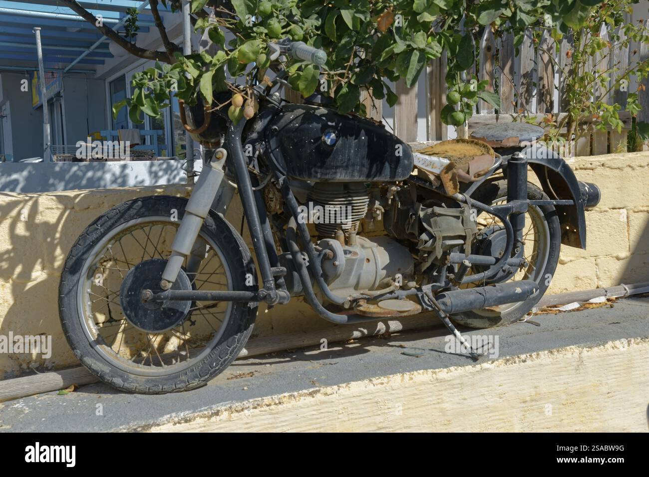 An old BMW R27 motorbike standing in the sun on a pavement, Karpathos ...
