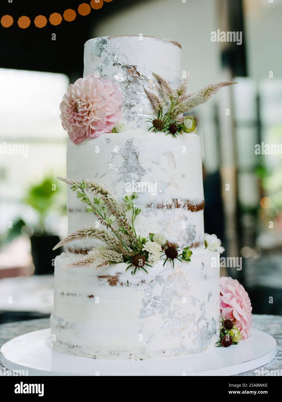 A beautifully designed three-tier wedding cake stands on a circular ...