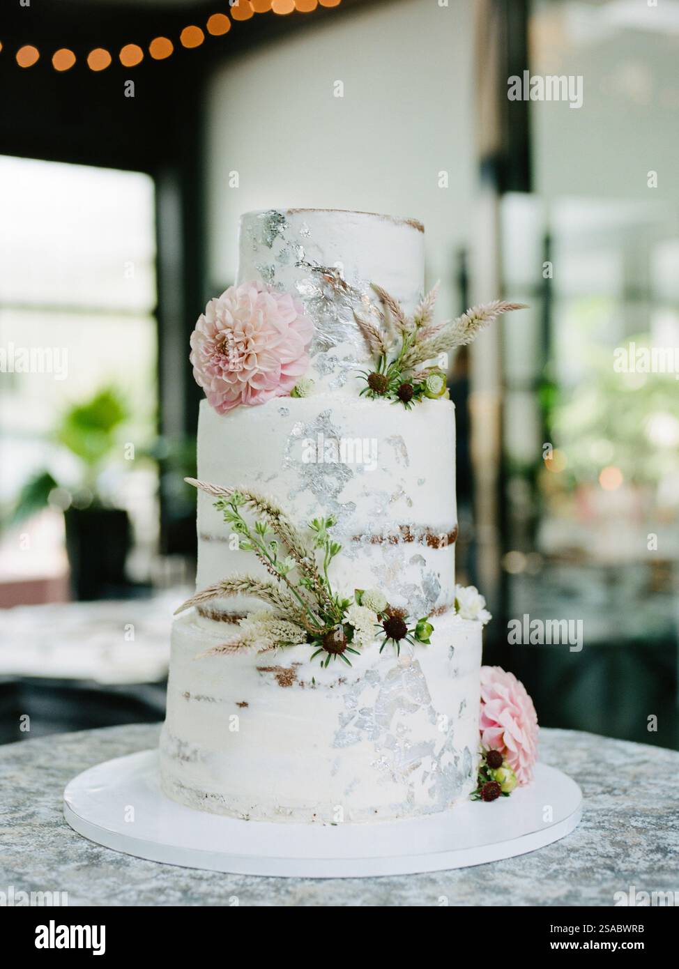A stunning three-tier wedding cake features elegant white frosting ...