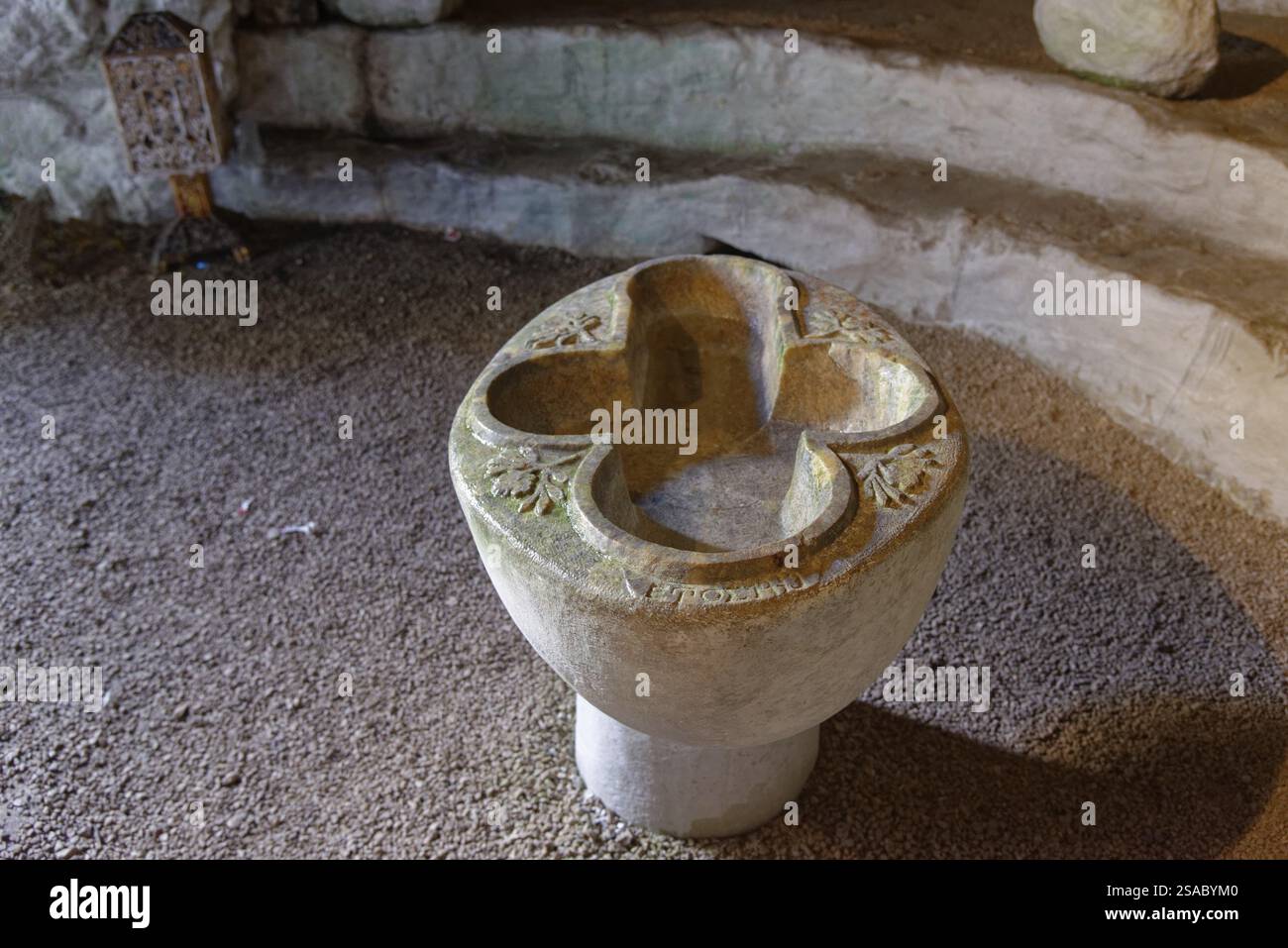 Artfully engraved stone baptismal font in the ancient style of the cave ...