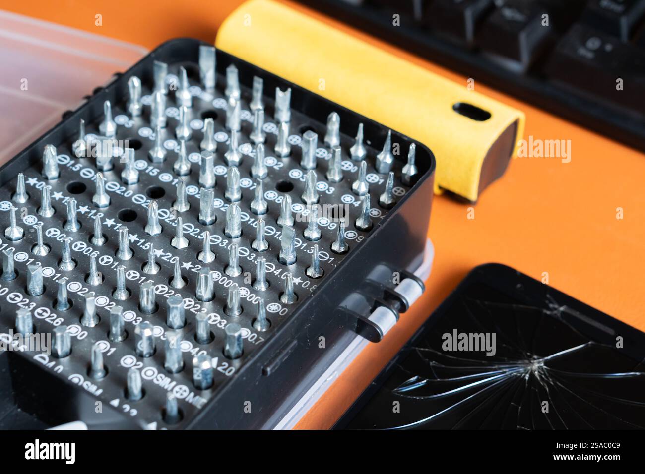 A close-up of a precision screwdriver set with multiple bits, a yellow ...
