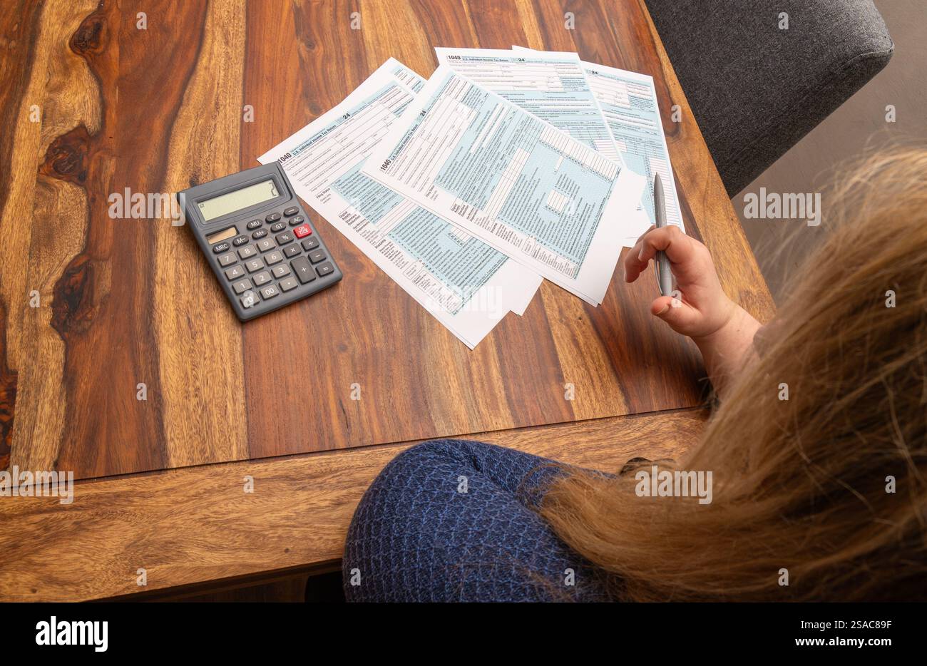 Perplexed Woman focused on completing 1040 US income tax form in a cozy ...