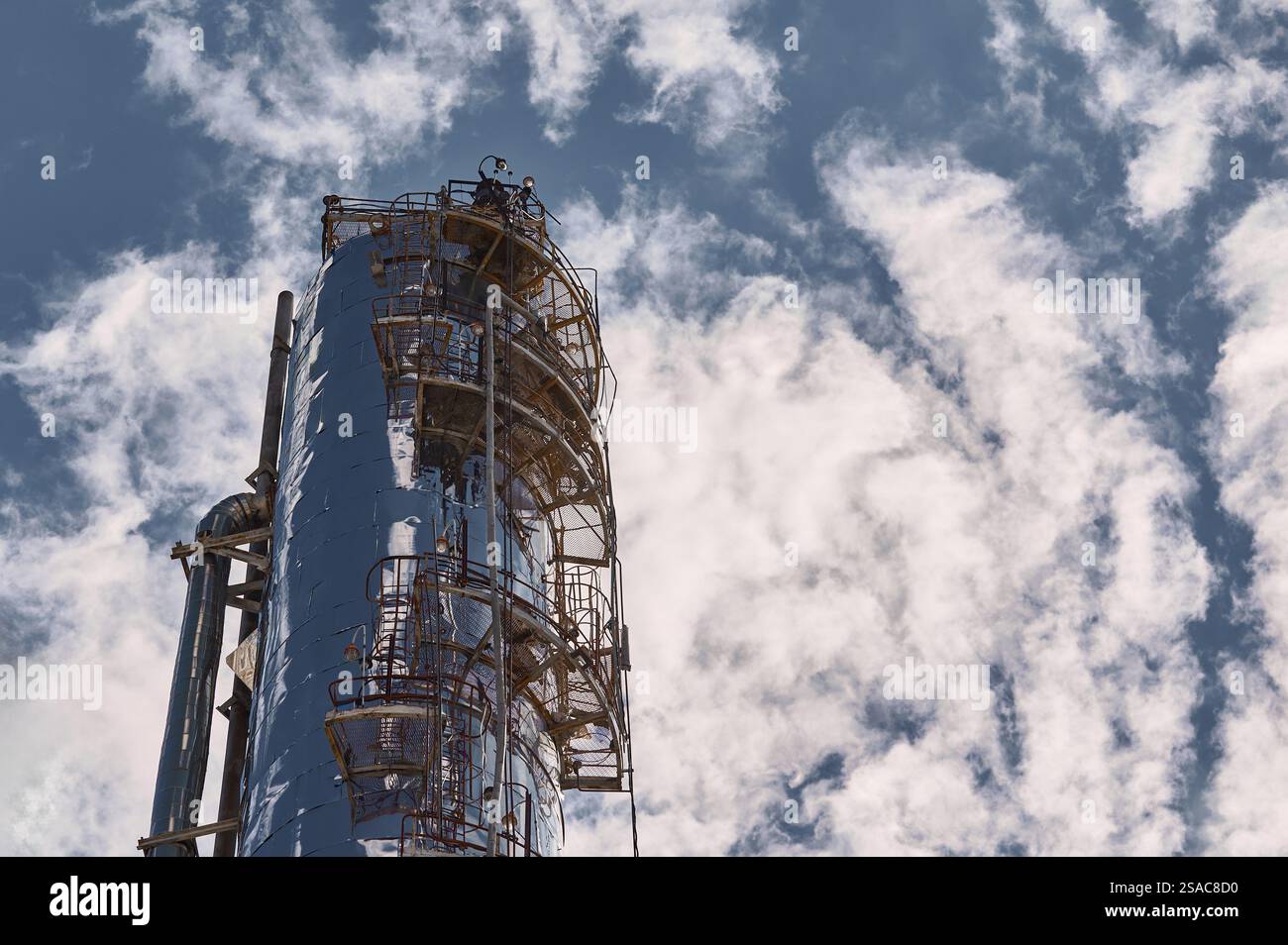 View of a chemical plant's distillation column against a cloudy sky ...
